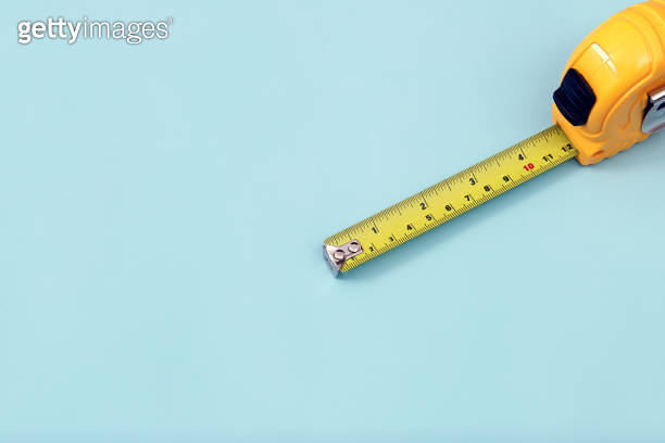 The yellow measuring tape for the mason is placed on a blue background ...
