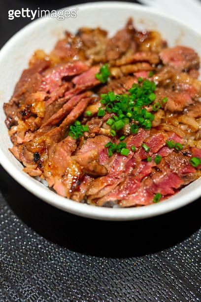 Japanese bowl of rice topped with beef steak medium rare served in ...