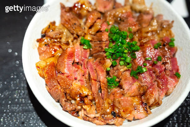 Japanese bowl of rice topped with beef steak medium rare served in ...
