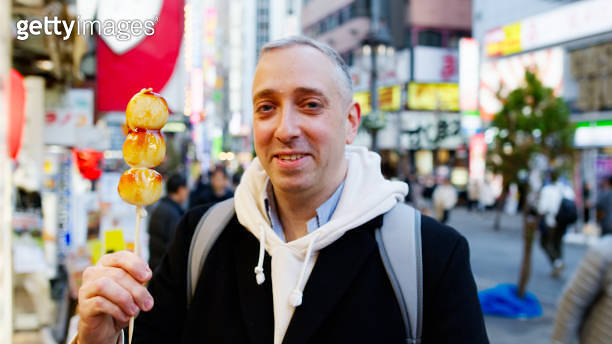 Middle Aged White Man Looking at Camera While Holding Glazed Dango ...