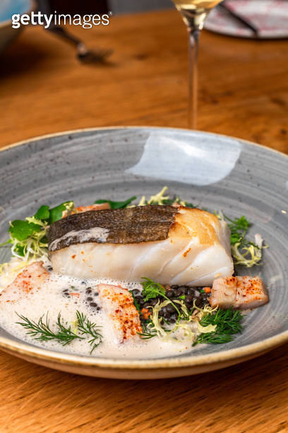 White fish fillet dish with lentils, foam sauce gravy served with wine ...