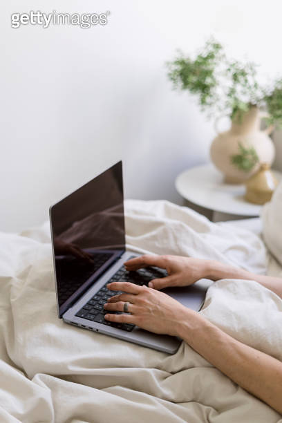Woman hands typing on laptop in comfort bed with bedding linen at ...