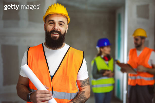 Portrait of construction site worker standing wearing safety vest and ...