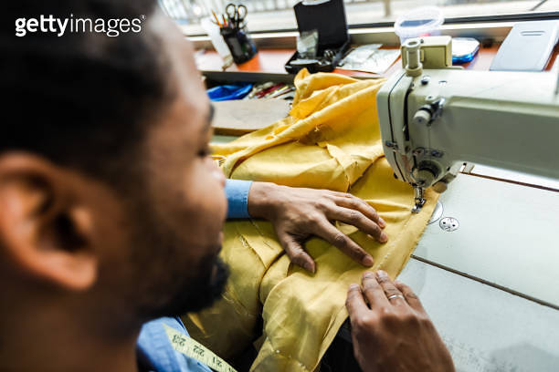 Young male African American tailor sew with a sewing machine in his own ...