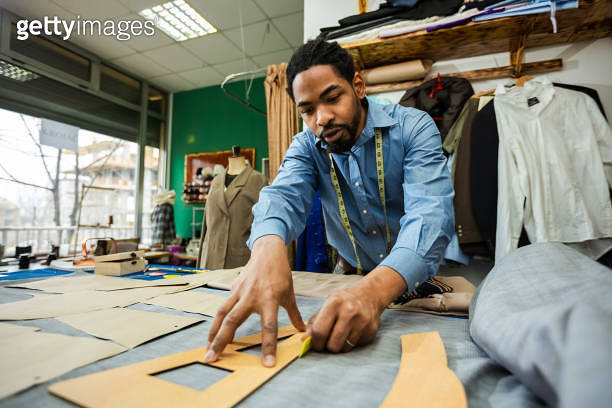 Male African American tailor measuring fabric with a ruler in his own ...
