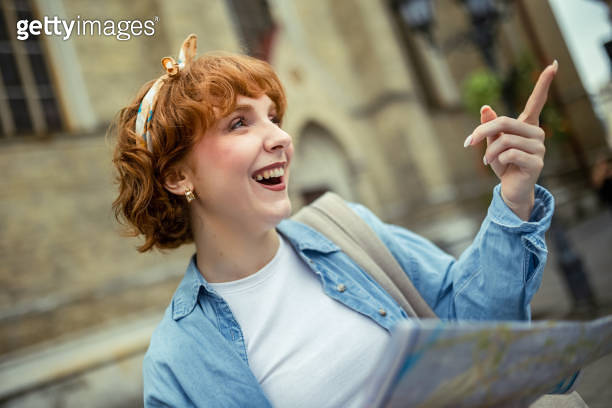 Female ginger tourist using a map while exploring city. (2173765989 ...