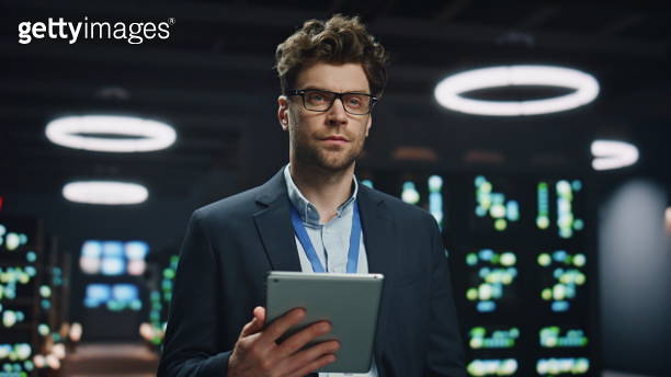 Smiling software engineer holding tablet computer in data center room ...