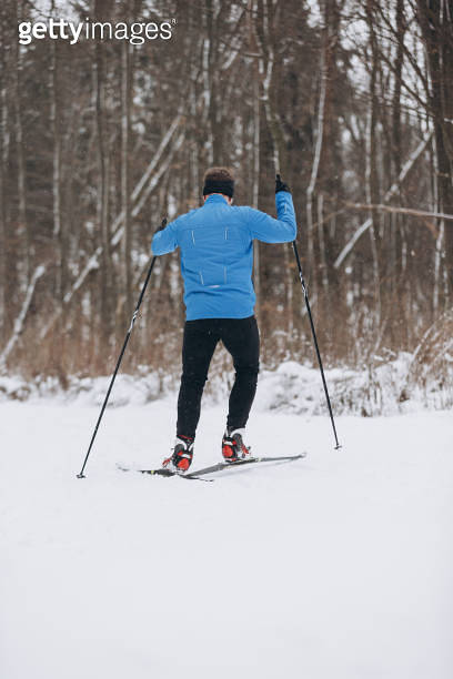 Back view of a male skier athlete skiing uphill on a cross-country ...