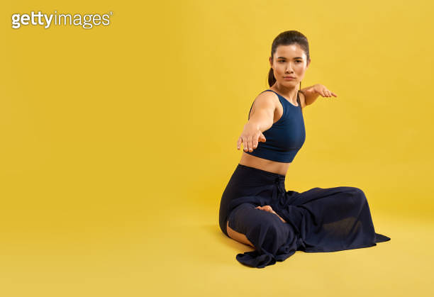 Girl holding right arm outstretched, while practicing yoga indoor. 이미지 ...
