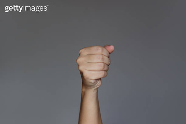 A fist-shaped female hand with clenched closed fingers making a gesture ...