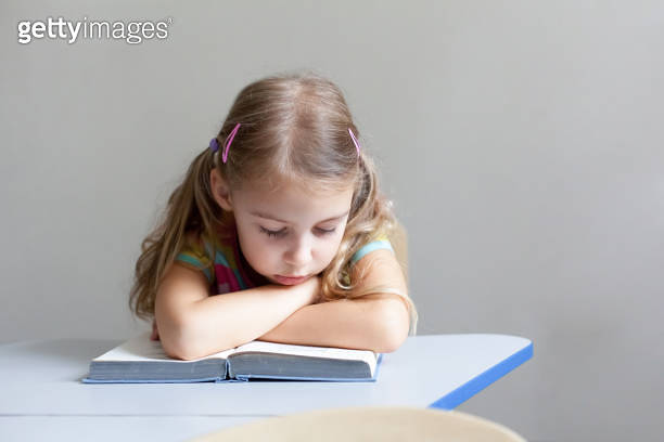 School child reading book on boring lesson. Tired pupil learning to ...