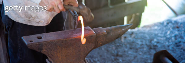 Panorama view blacksmith man hand using long carbon steel tongs with ...