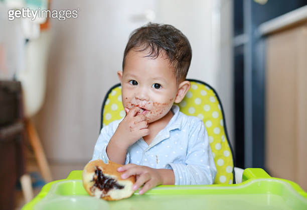 Happy Asian little baby boy sitting on children chair indoor eating ...