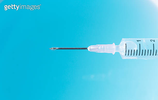 Close-up of syringe needle on isolated blue background,A doctor's hand ...