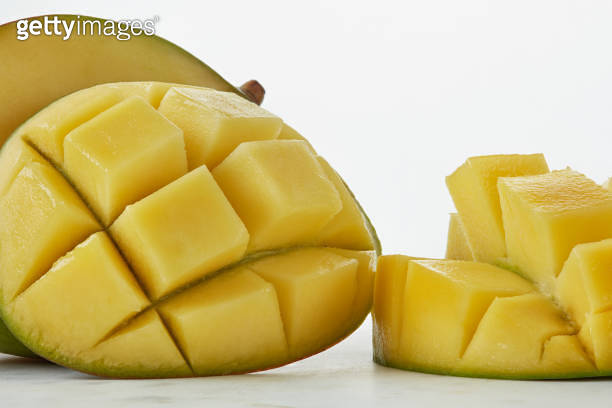 Close up of fresh ripe mango fruits, cross section cutting mango cubes ...