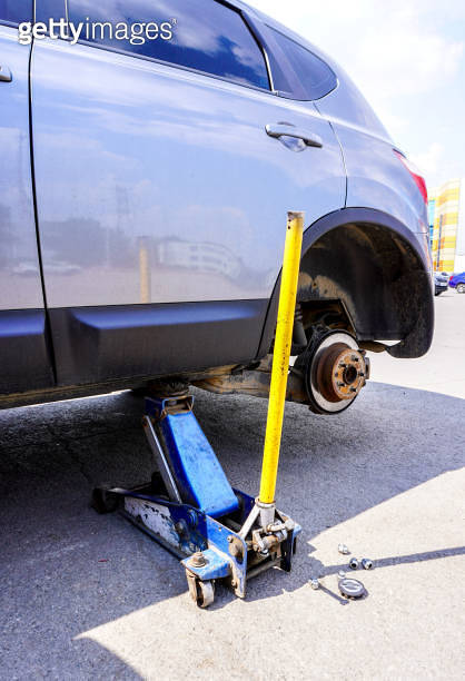 Wheels replacement. Lifting car and changing wheels using trolley jack ...