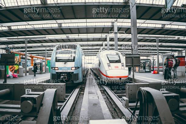 Two modern trains stand side-by-side on tracks in a large indoor train ...