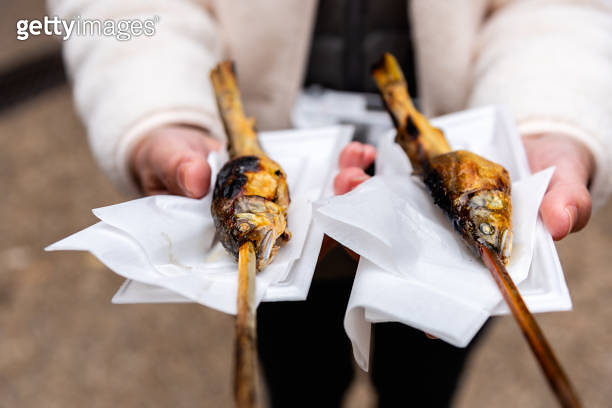 Ayu fish grilled with salt, in woman hand. Japanese ayu sweetfish a ...