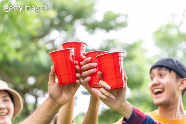 Close up hands of diverse group friends clinking a beer cup together ...