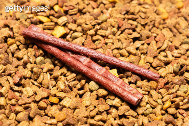 Treats for cats meat sticks sausages against the background of dry food ...