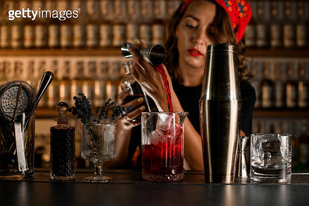 Cute female bartender pouring red wine from jigger into cocktail mixing glass with ice cubes 이미지 ...