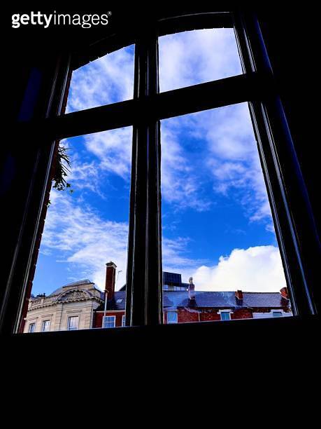 Looking out of an old window at blue sky and buildings in West ...