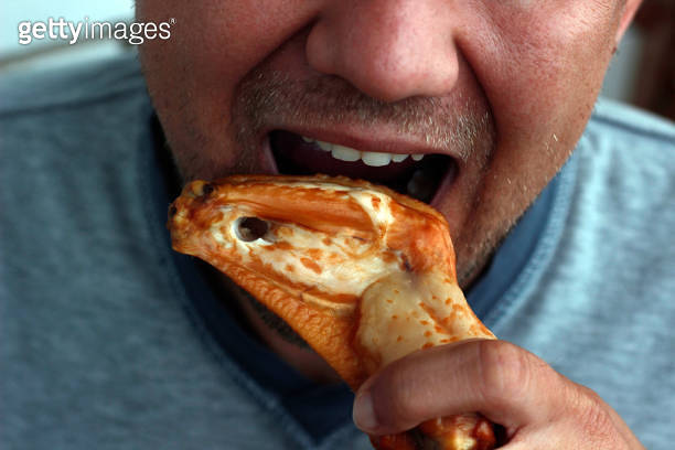man eating smoked chicken wing, man's mouth biting chicken wing close ...