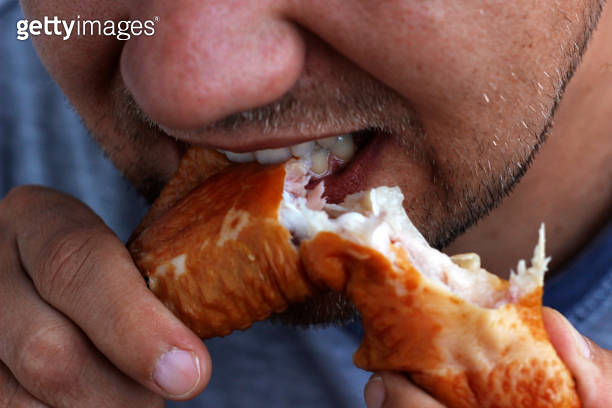 man eating smoked chicken wing, man's mouth biting chicken wing close ...