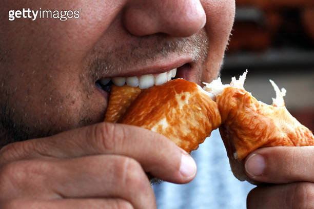 man eating smoked chicken wing, man's mouth biting chicken wing close ...