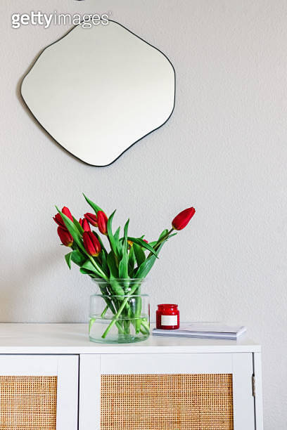 Minimalist living room with a fluid shape mirror on the wall and red ...