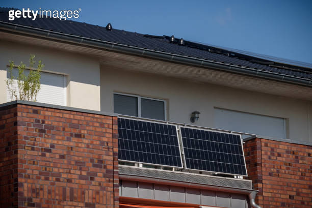 Modern residential building with solar panels on a balcony railing and ...