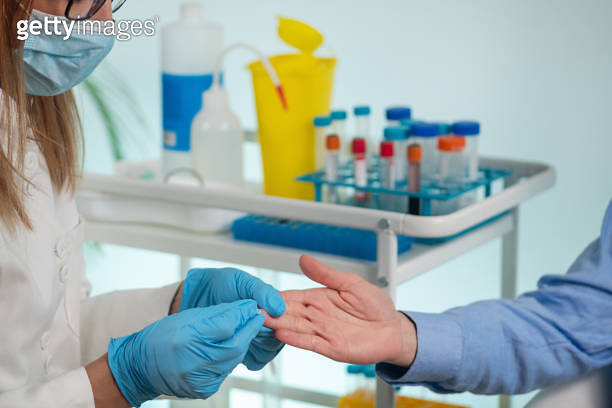Nurse draws blood sample from patient's finger with finger prick method ...