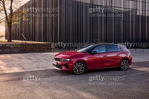 Red Opel Astra hatchback, parked in front of the modern building. Model ...
