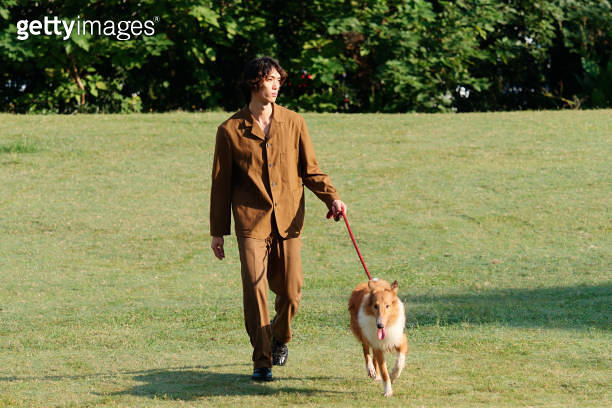 Portrait of a handsome Chinese young man walking with his rough collie ...