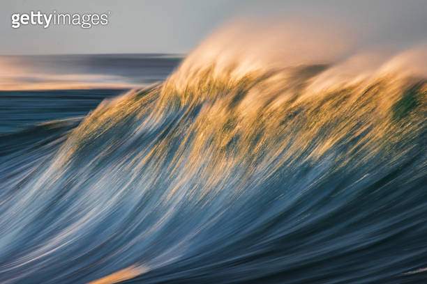 Slow shutter blur of smooth offshore wave forming over reef in the ...