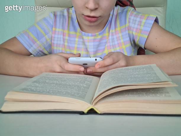 Dependent child teenage girl with smartphones refuses to read book and ...
