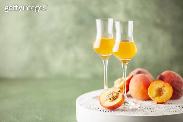 Peach liqueur in grappas glasses and fresh peaches on the table. Copy ...