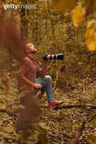 Man using binoculars and camera for bird and animal watching in nature ...