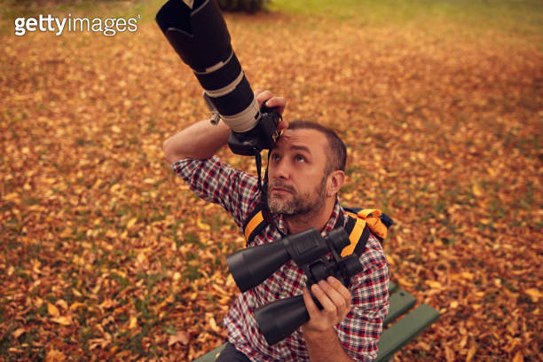 Man using binoculars and camera for bird and animal watching in nature ...