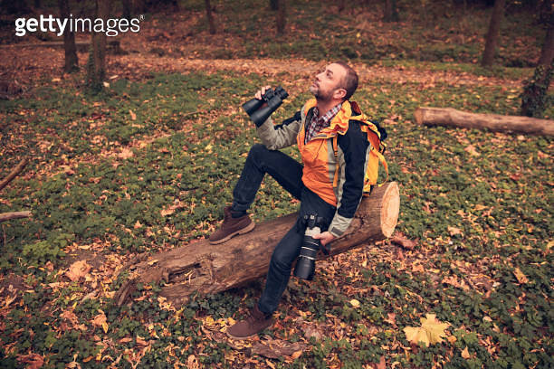 Man using binoculars and camera for bird and animal watching in nature ...