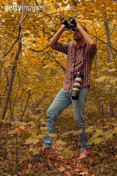Man using binoculars and camera for bird and animal watching in nature ...