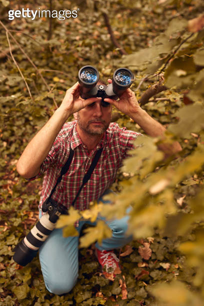 Man using binoculars and camera for bird and animal watching in nature ...