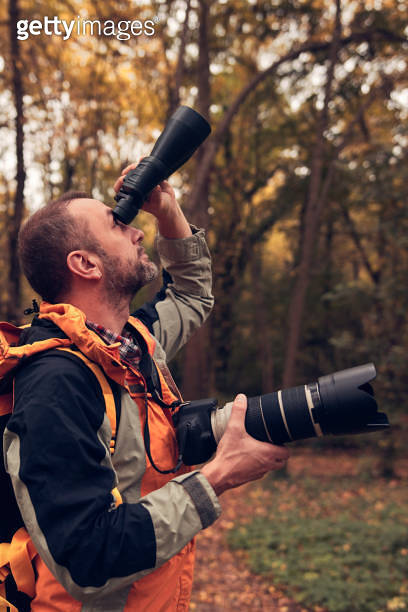 Man using binoculars and camera for bird and animal watching in nature ...
