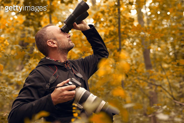 Man using binoculars and camera for birdwatching and other observing ...