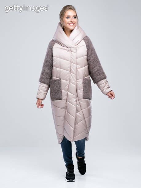 Female portrait in studio, woman wear winter rose coat. Grey background ...