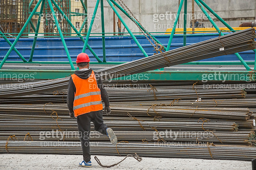 A construction worker steps over a piece of lying wire on a ...