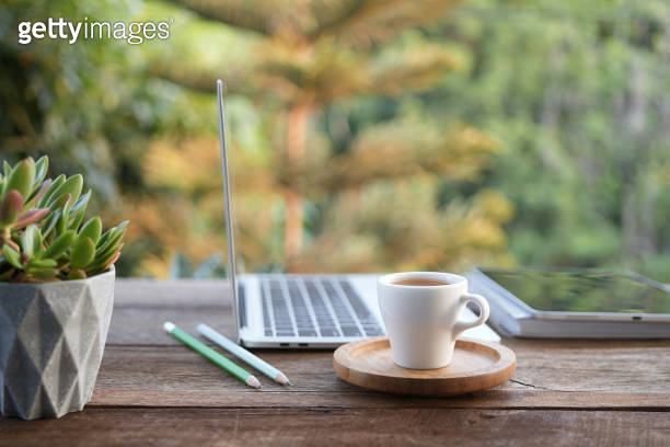 Laptop side view and coffee cup with notebooks on white table outdoor ...