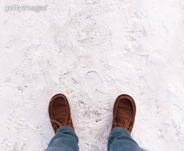 Feet in boots on asphalt covered with snow. 이미지 (2017166681) - 게티이미지뱅크