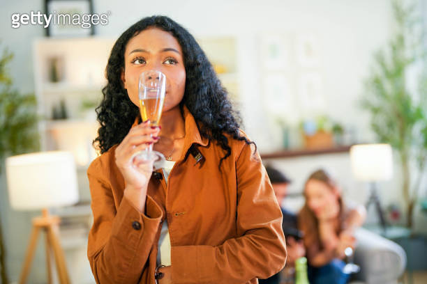 Charming hostess with a drink in hand, sharing a genuine smile ...