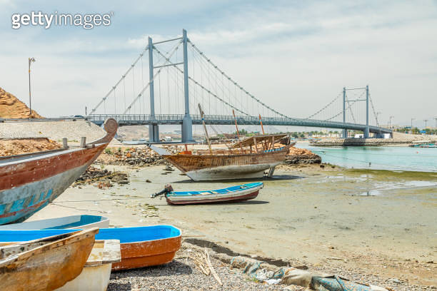Al Ayjah bridge and traditional omani wooden dhow boats on a seashore ...